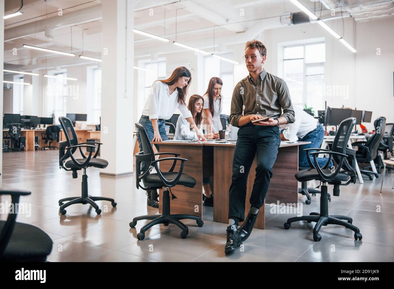 Young male employee in formal clothes standing in the office. Group of ...