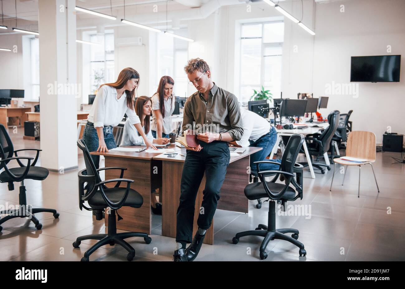 Young male employee in formal clothes standing in the office. Group of ...