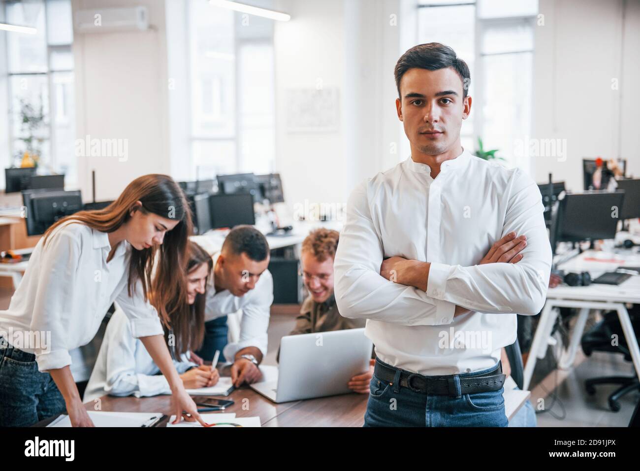 Young male employee in formal clothes standing in the office. Group of ...