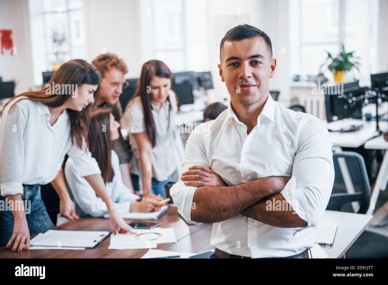 Young male employee in formal clothes standing in the office. Group of ...