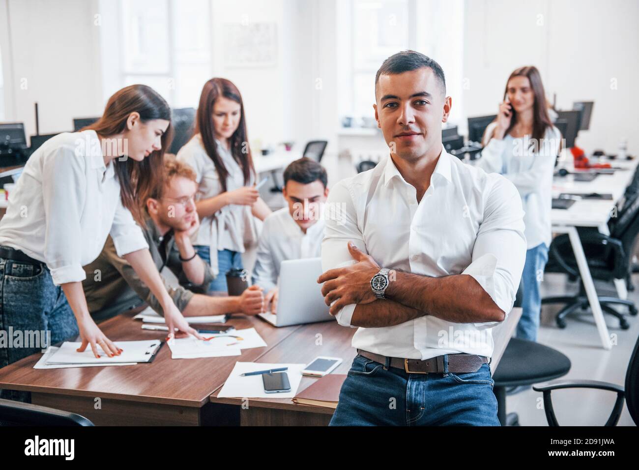 Young male employee in formal clothes standing in the office. Group of ...