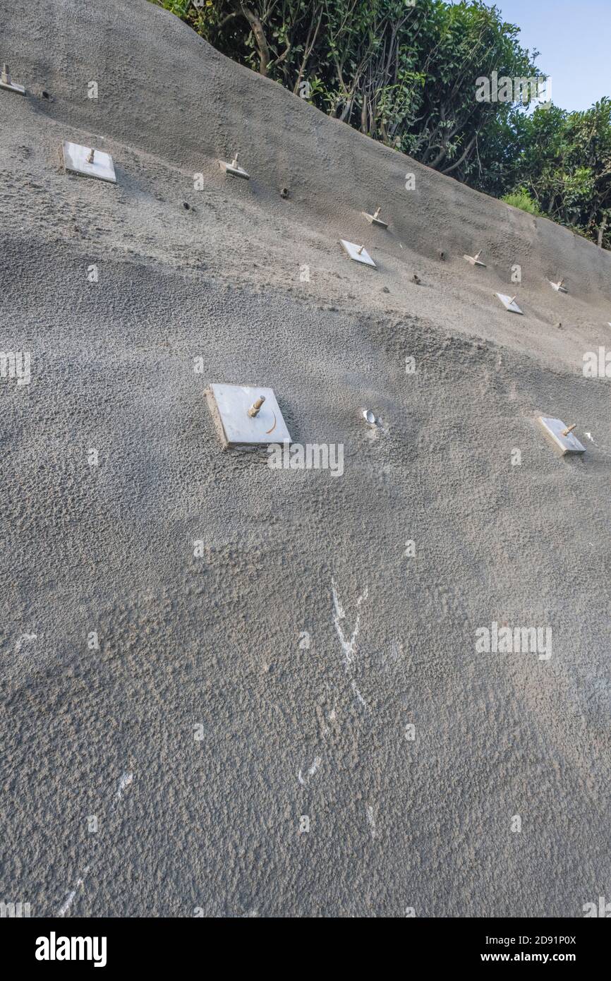Cement clad chain link rockfall protection with anchors visible on the ...