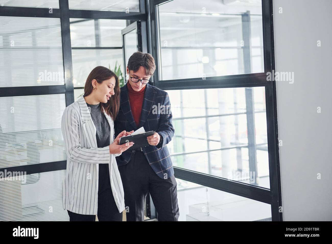 Two office workers in formal clothes indoors have a busy working day ...