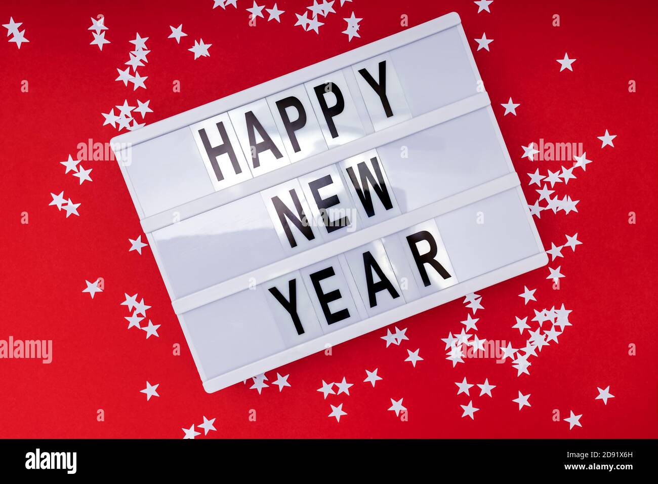 Happy New Year text on a lightbox with white star shaped confetti decor ...