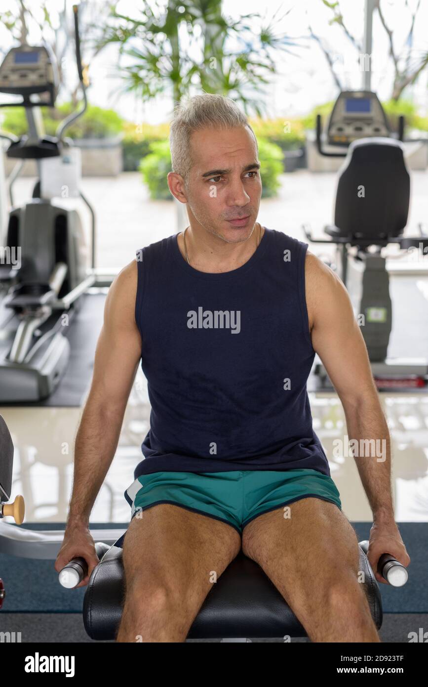 Mature handsome Persian man doing leg extension exercise Stock Photo ...