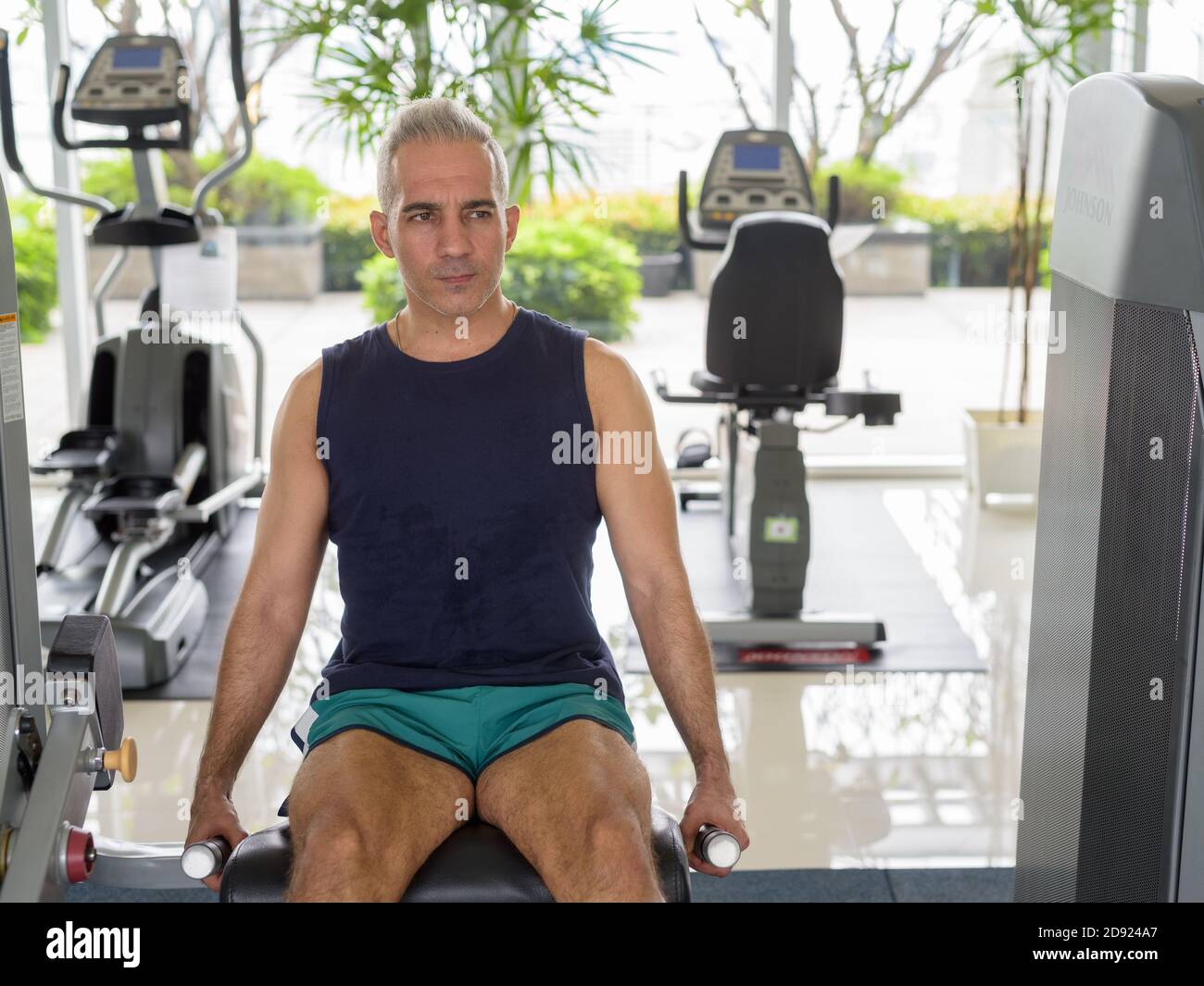 Mature handsome Persian man doing leg extension exercise at the gym ...