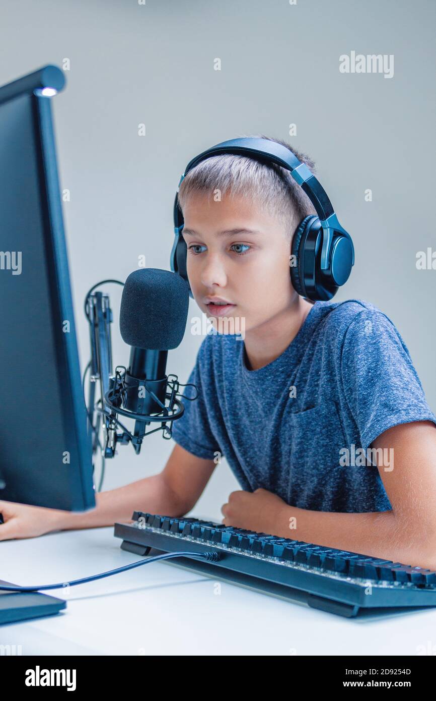 Teenage boy talks looking to computer monitor screen. Kid wearing ...