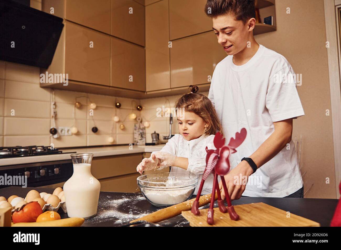 Brother with his little sister preparing food by using flour on kitchen ...