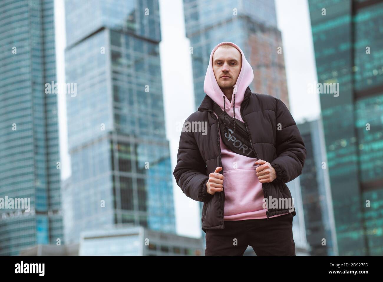 Handsome casual man in black jacket and pink hoody standing on a ...