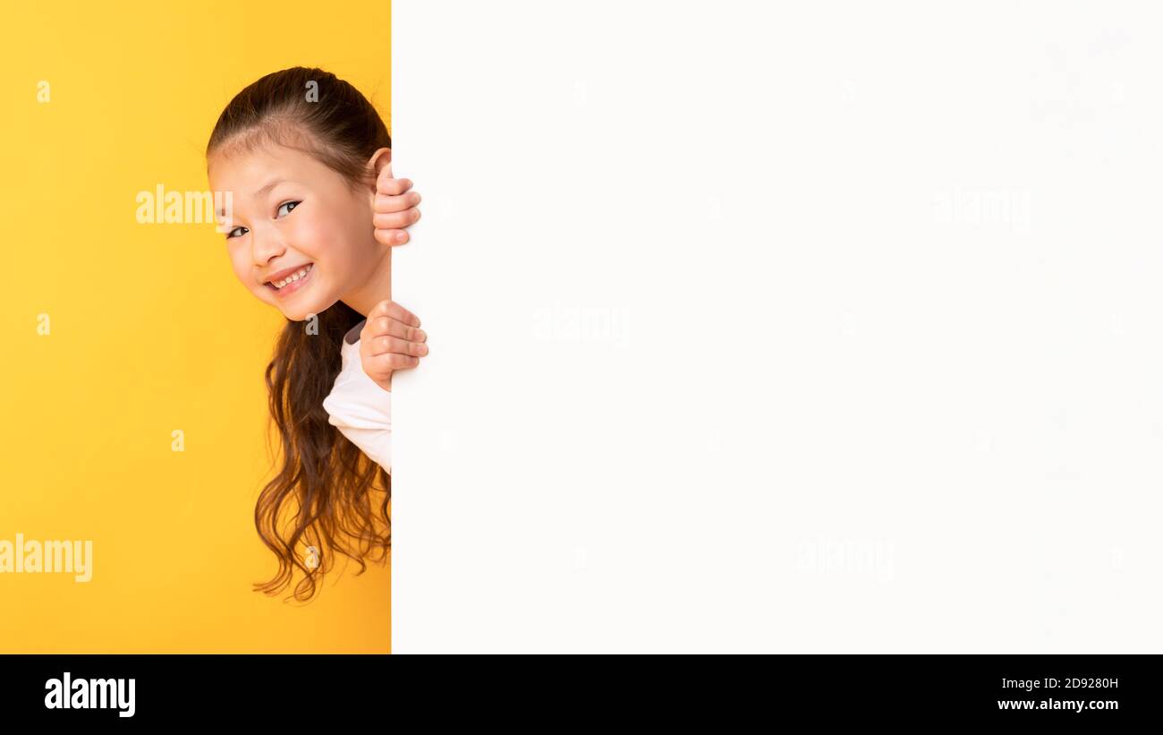 Asian kid hiding behind blank white advertising billboard Stock Photo ...