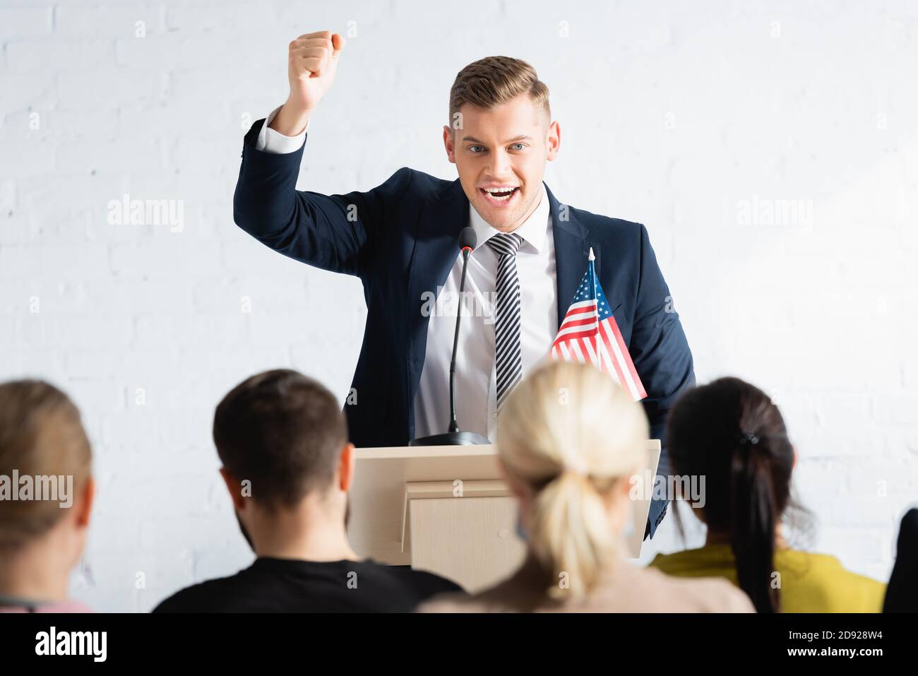 excited speaker showing winner gesture while talking to agitators in ...