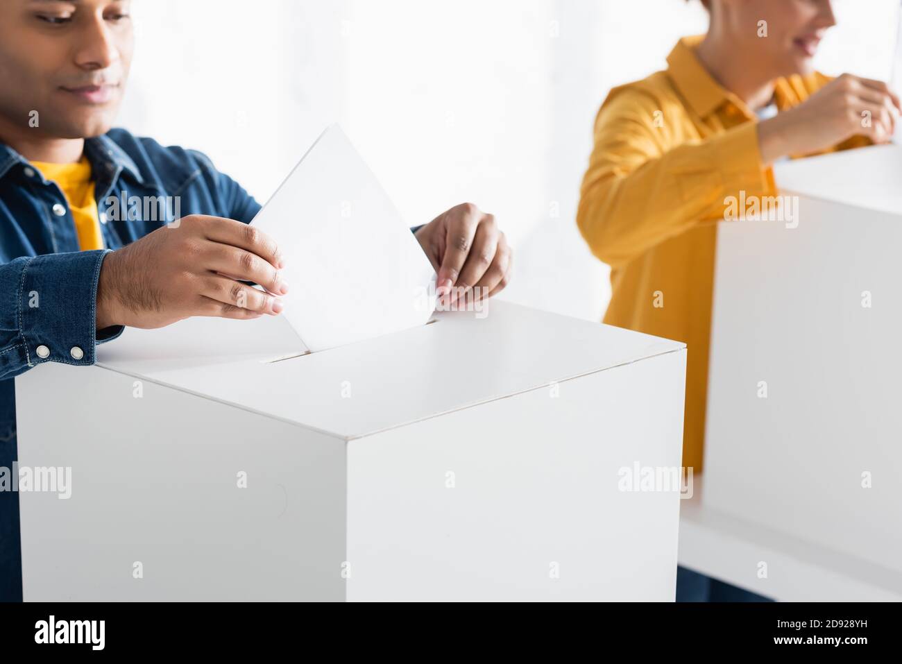 indian man inserting ballot into polling box near woman on blurred ...