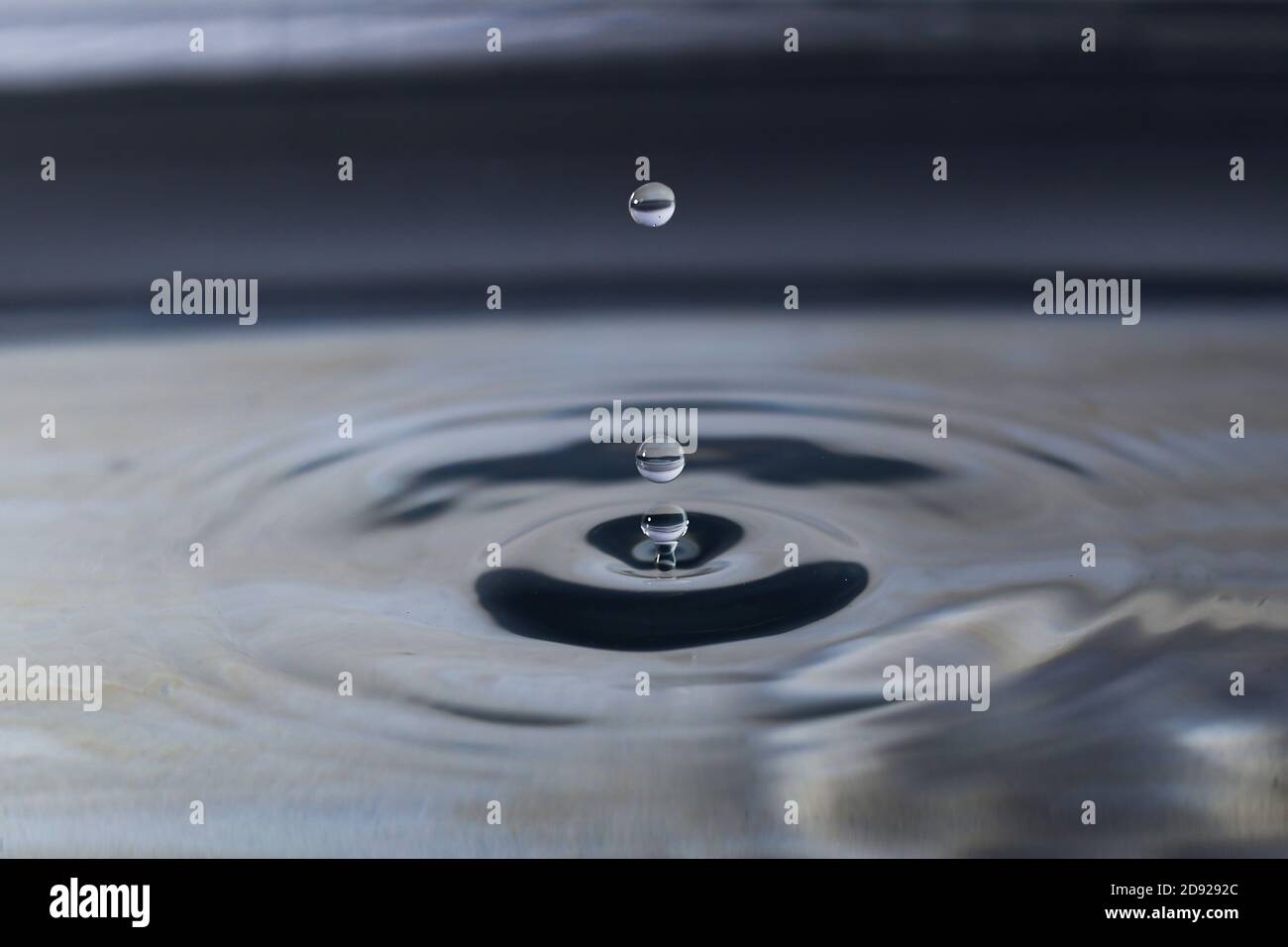 Small water drop on water surface creating ripples Stock Photo - Alamy