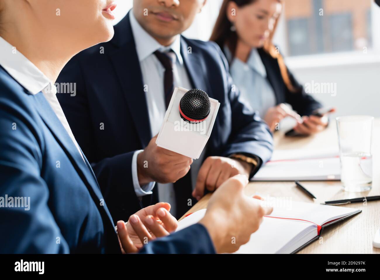 partial view of indian journalist with microphone interviewing ...