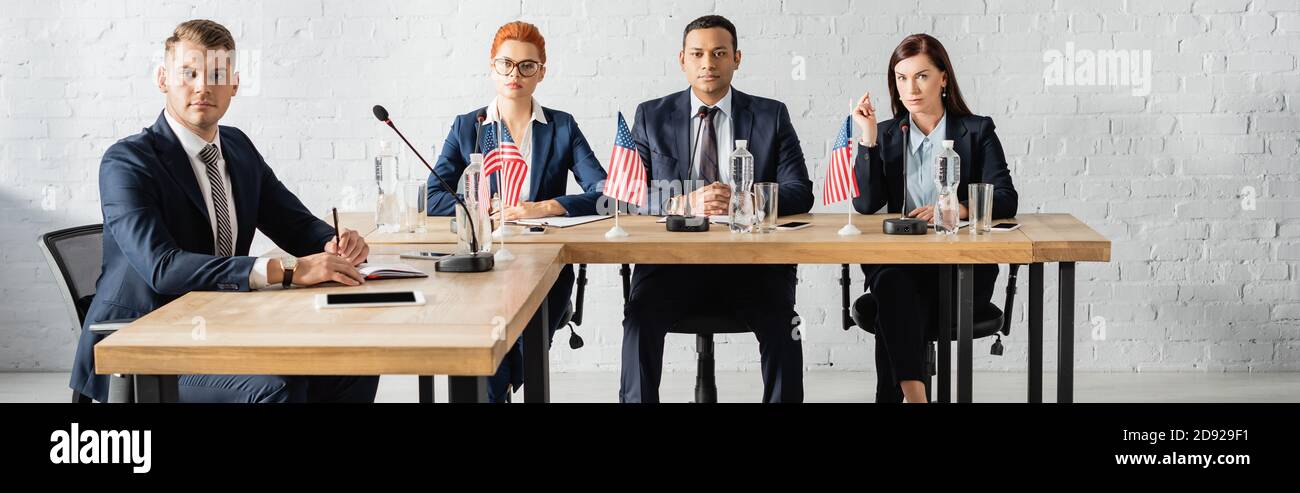 Political party members looking at camera, while sitting at table in ...