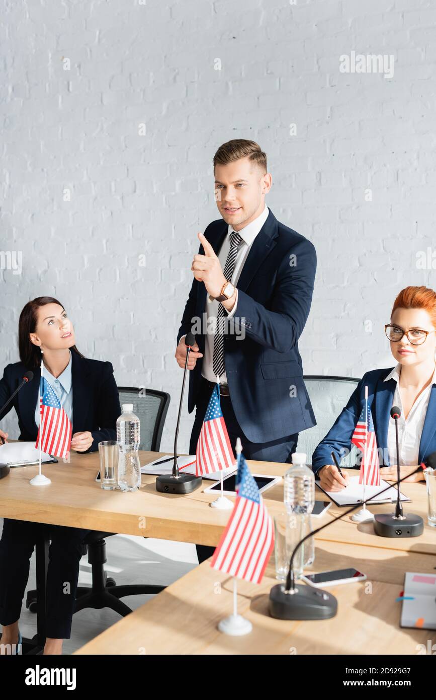 Smiling politician pointing with finger, speaking while standing near ...