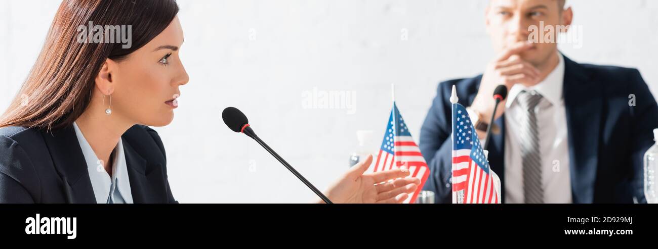 Female politician gesturing, while speaking in microphone, sitting near ...
