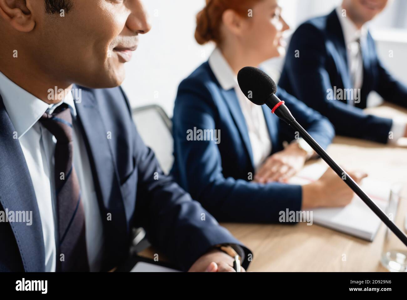 Positive indian politician sitting near microphone with blurred ...
