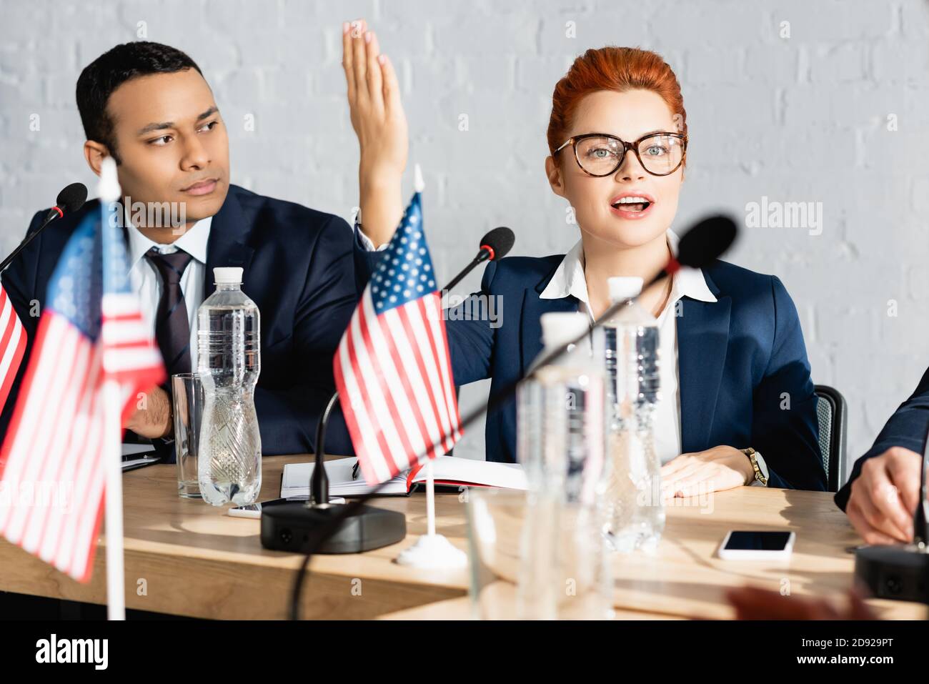 Indian politician looking at redhead woman with raised hand, while ...