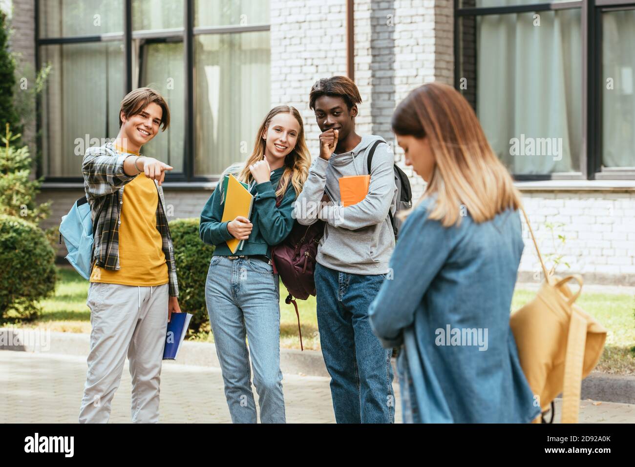 Selective focus of smiling multicultural teenagers with backpacks ...