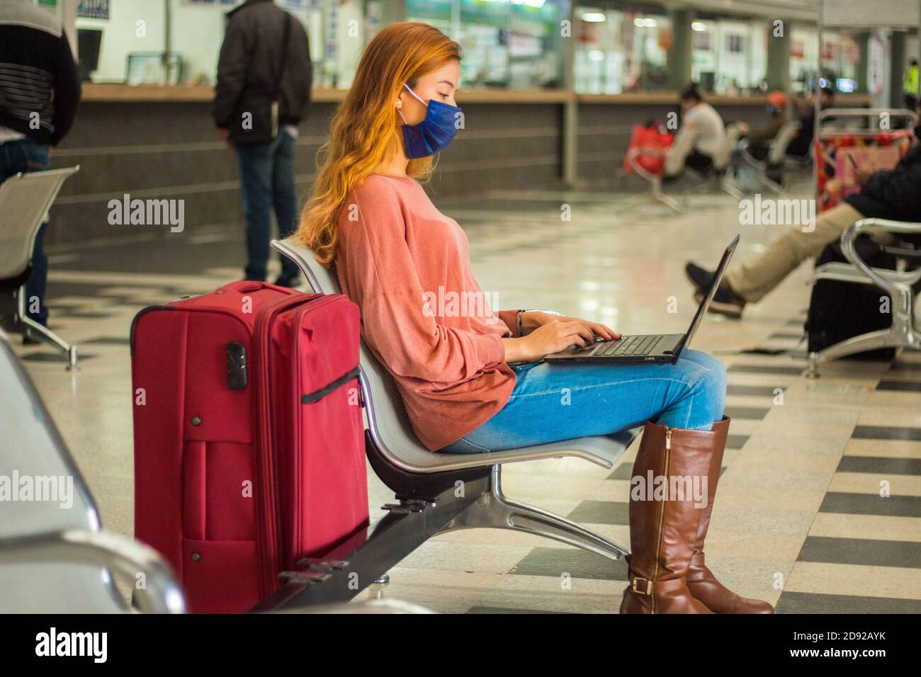 Traveller wearing a mask working on her laptop and waiting for her ...
