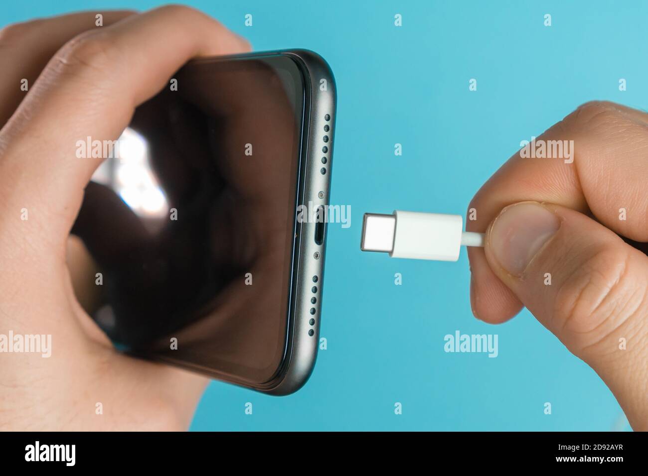 Close up mans hand inserting a charger into the mobile phone through a ...