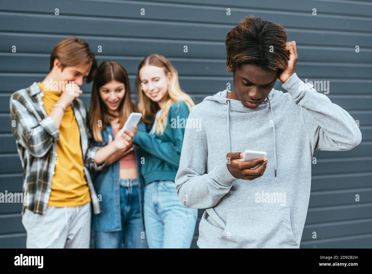 Selective focus of upset african american boy using smartphone near ...