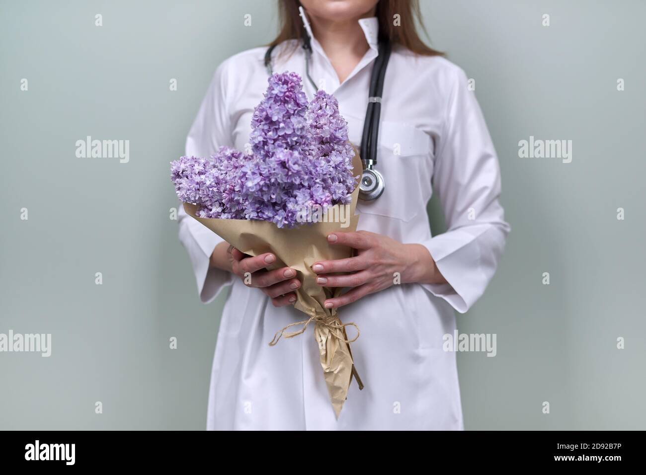Bouquet of lilac flowers in the hands of female doctor with stethoscope ...