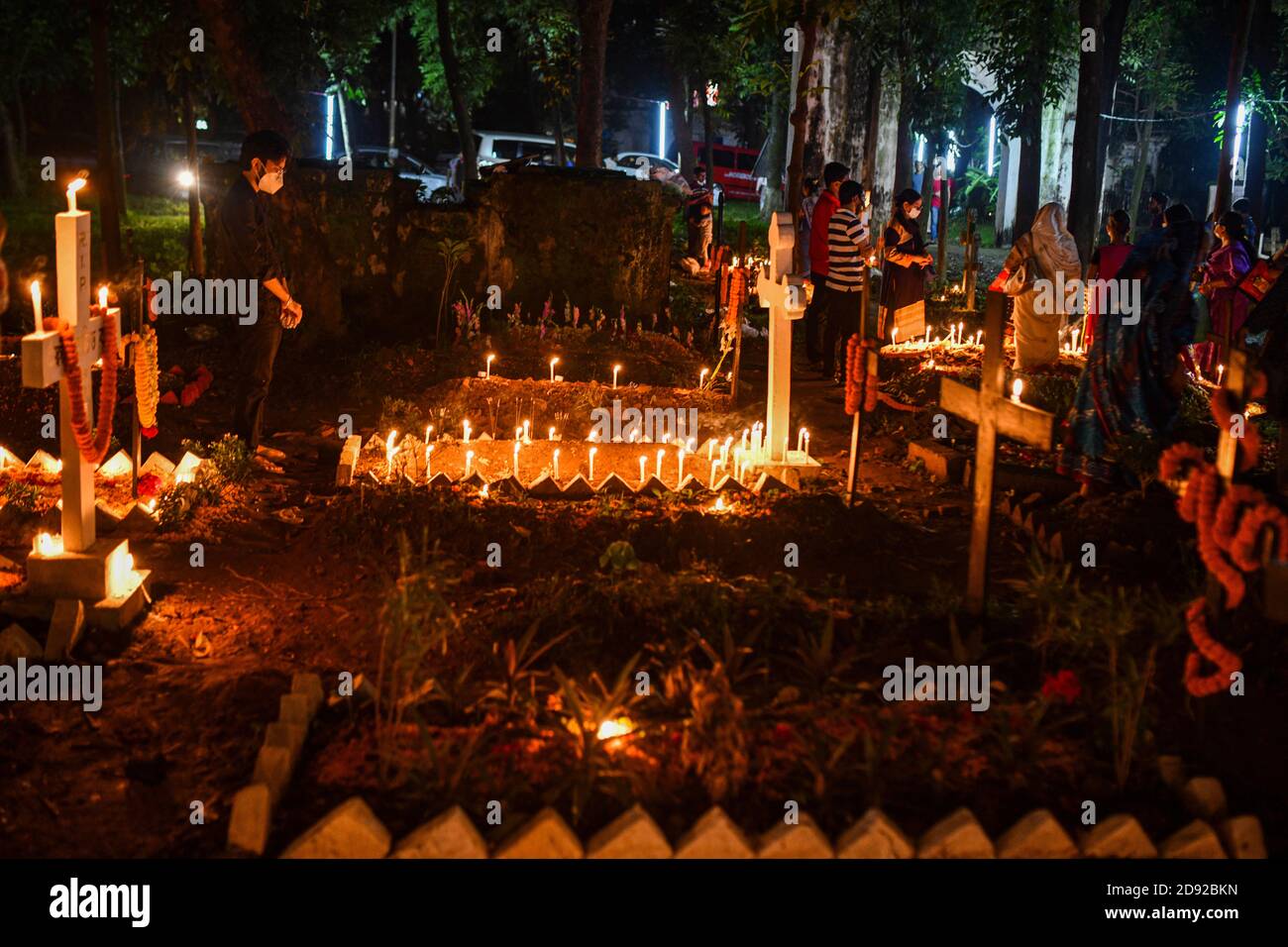 A christian family offer prayers and light candles by the grave of a ...