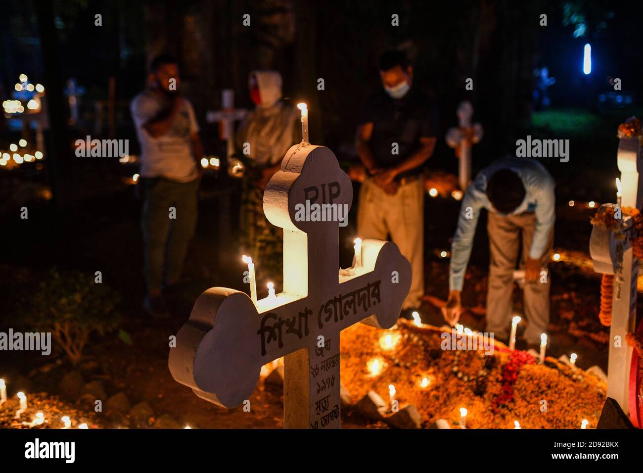 A christian family offer prayers and light candles by the grave of a ...