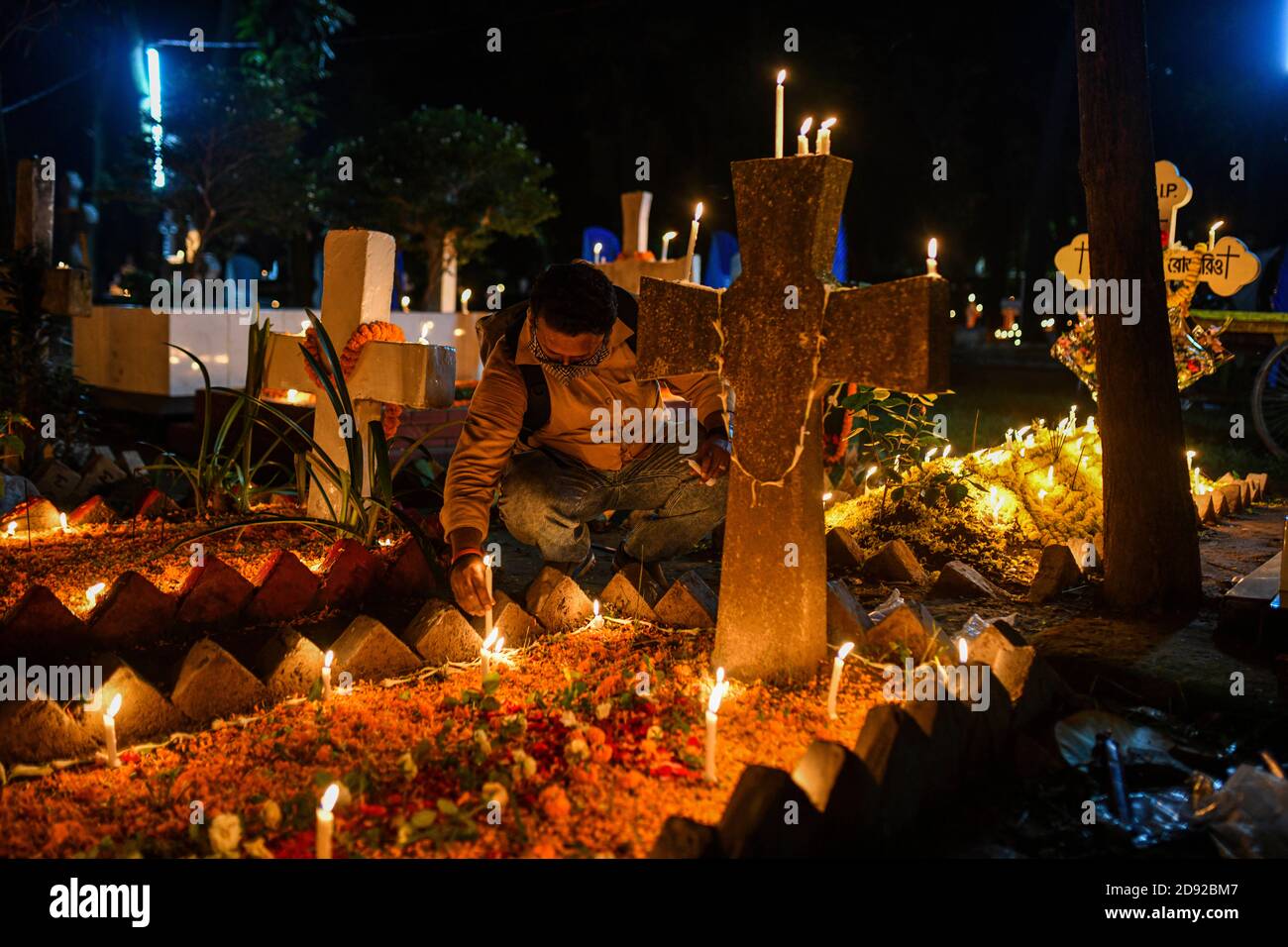 A Christian man lights candles by the grave of a relative during the ...