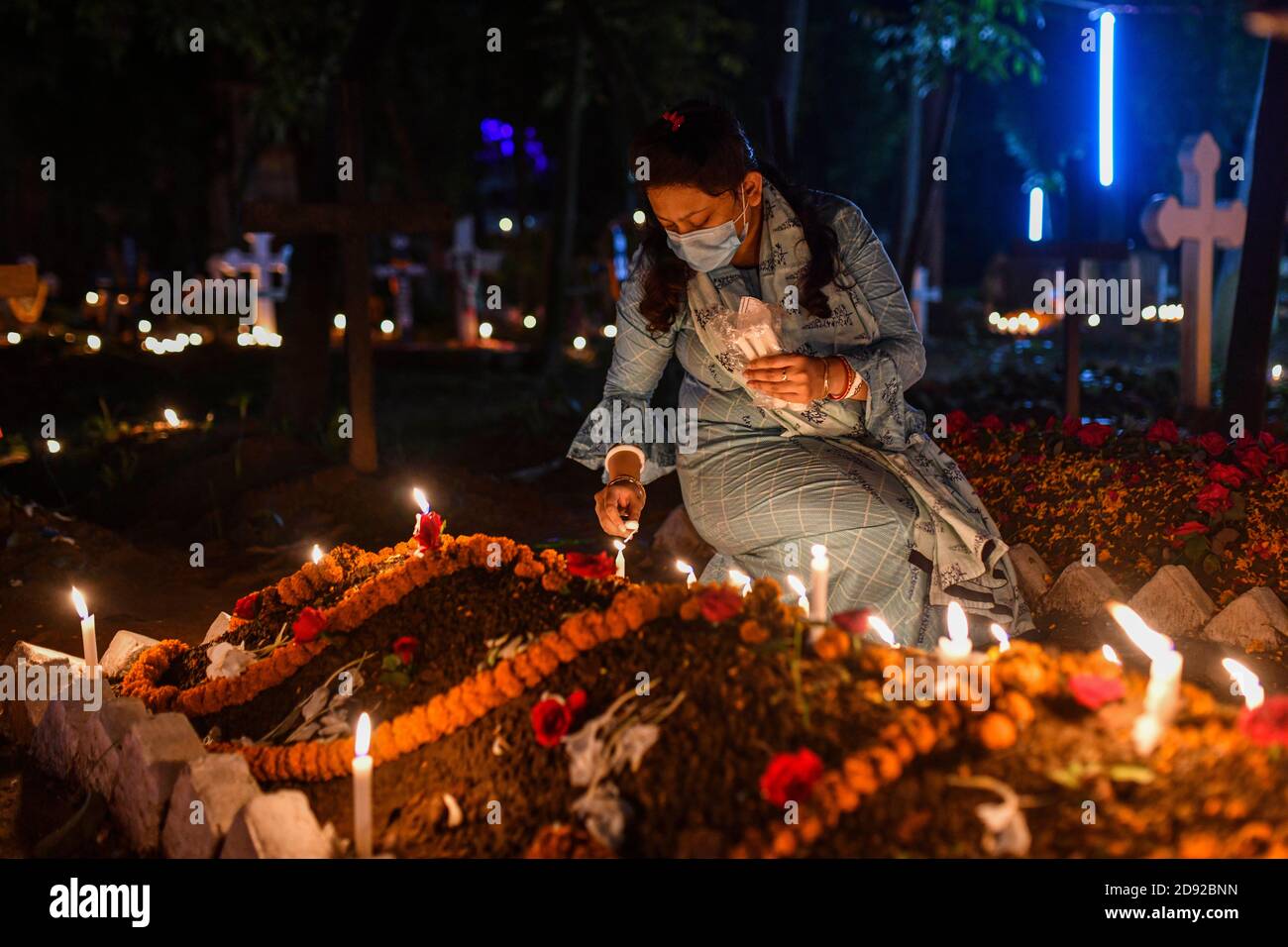 A christian woman lights candles by the grave of a relative during the ...