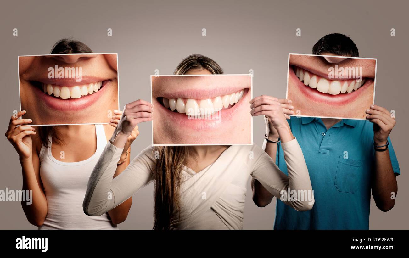 three happy people holding a picture of a mouth smiling on a gray ...
