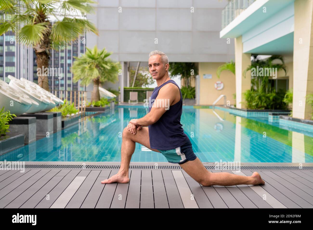Mature handsome Persian man stretching at the swimming pool Stock Photo ...
