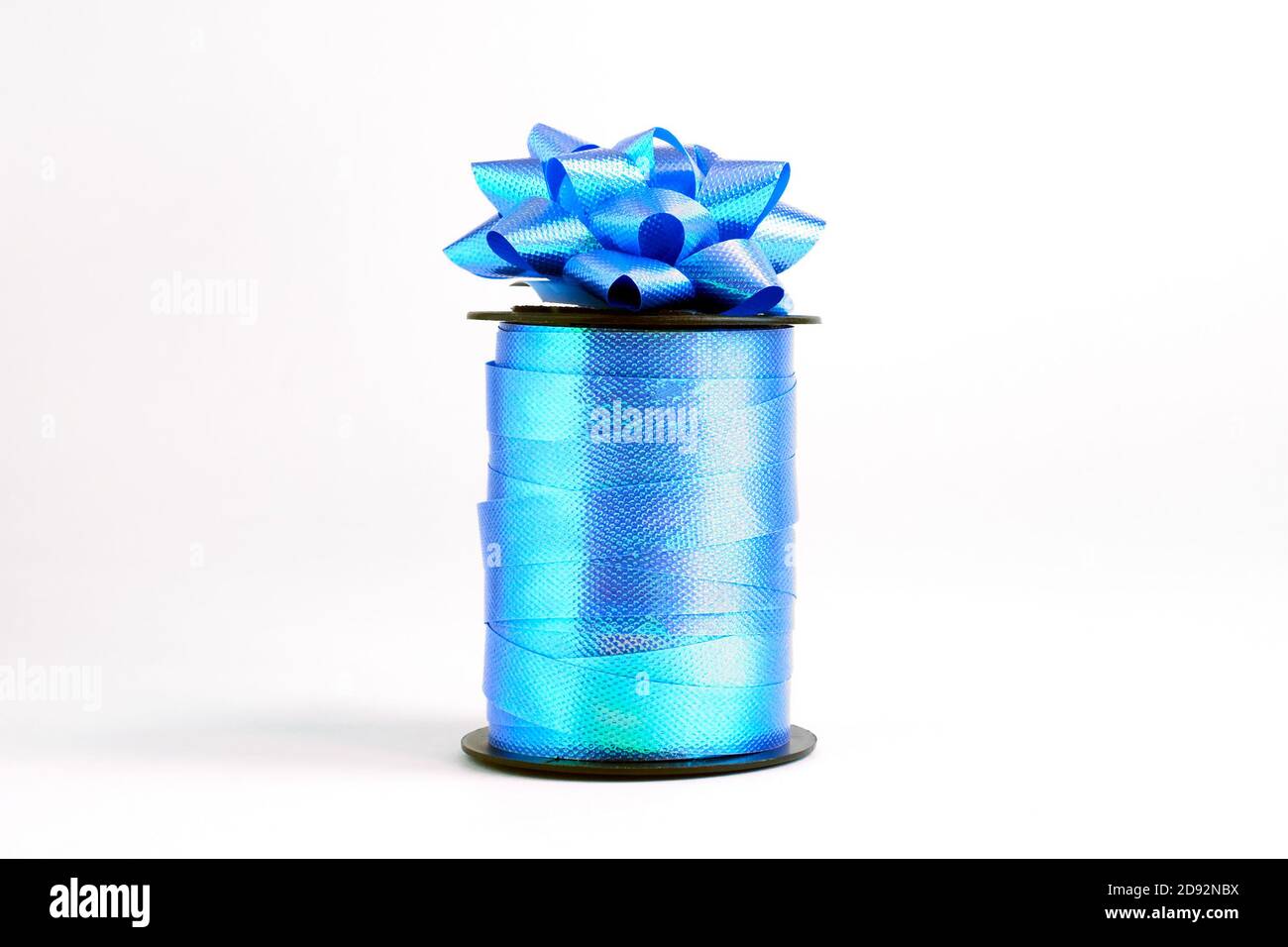Spool of blue curling ribbon roll and decorative gift bow on white ...