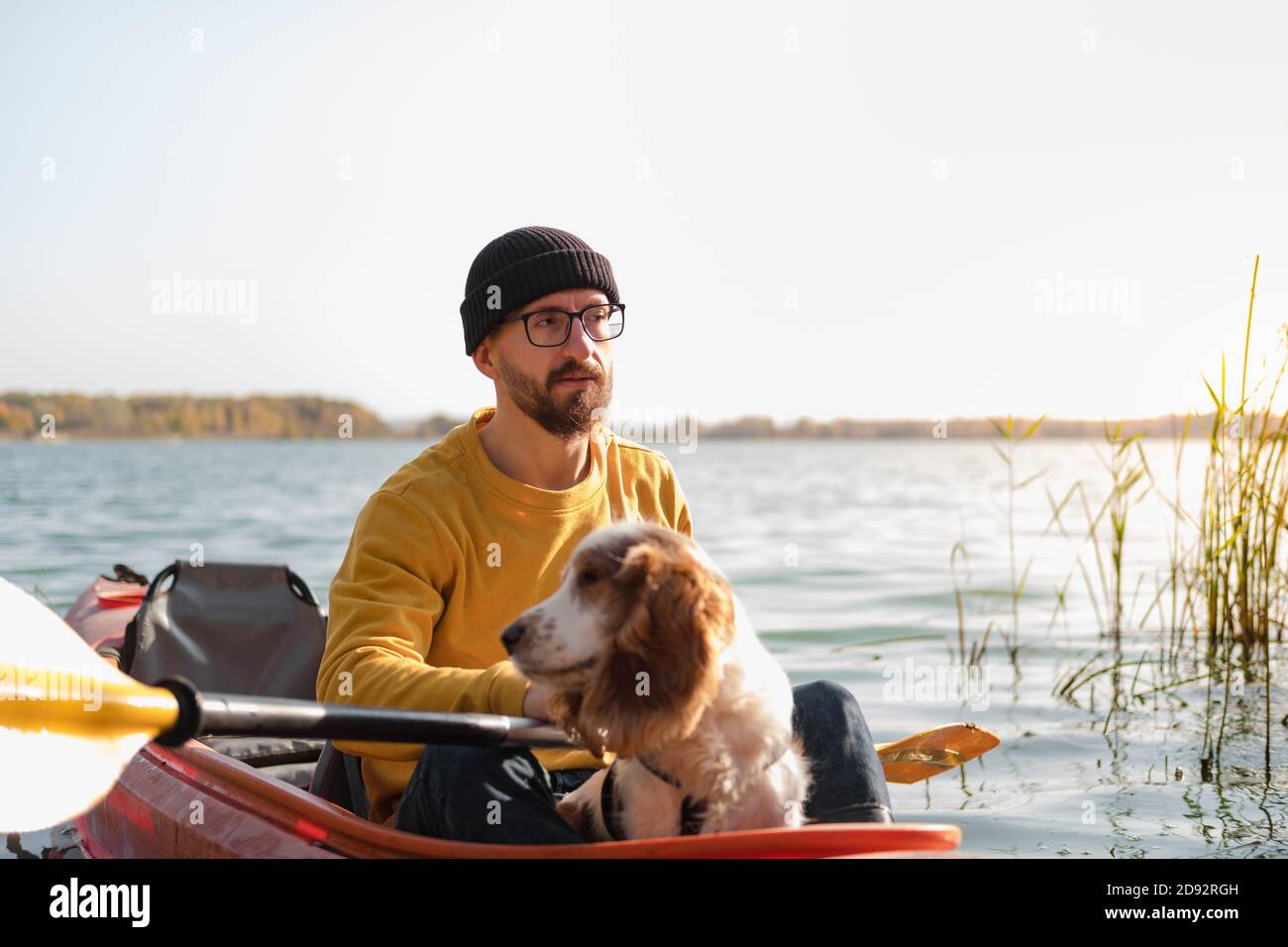 Man with a dog in a canoe on the lake. Young male person with spaniel ...