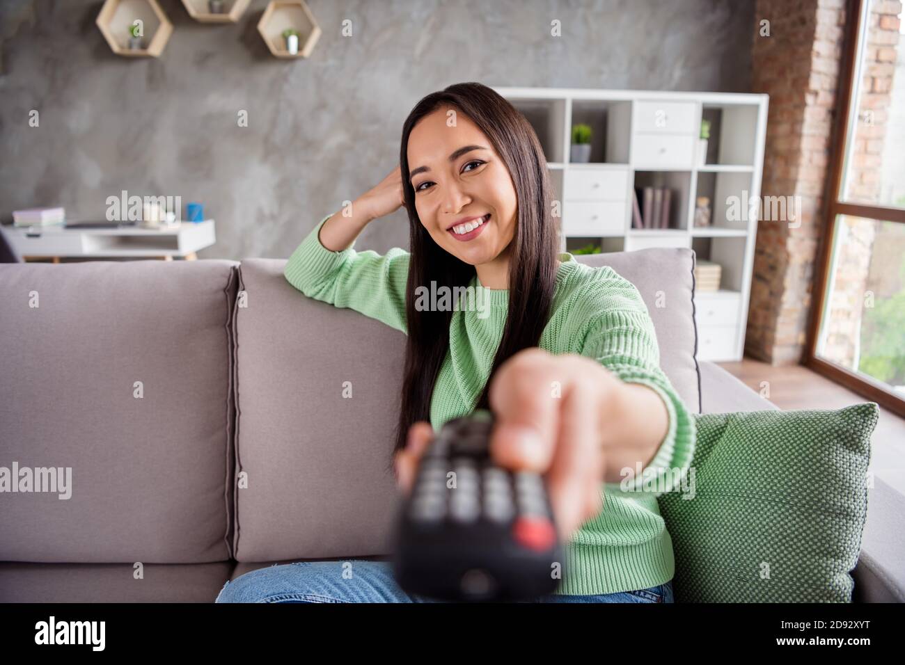 Portrait of nice charming content chinese girl sit divan watch tv ...