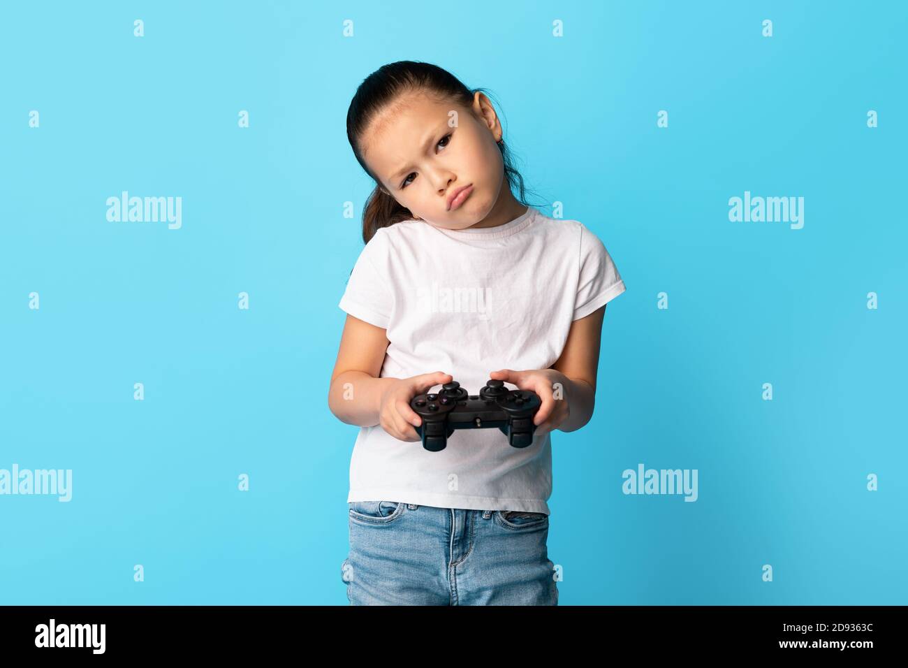 Bored asian kid playing video game using joystick Stock Photo - Alamy