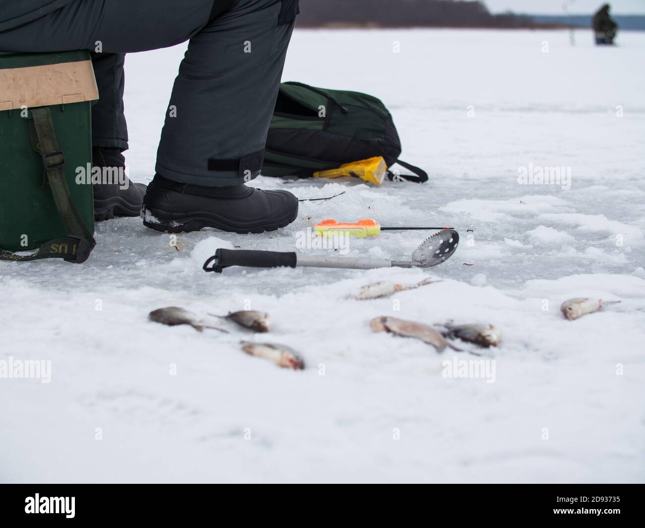 Winter ice fishing, lake, frosty day. fisherman collects gear in the ...
