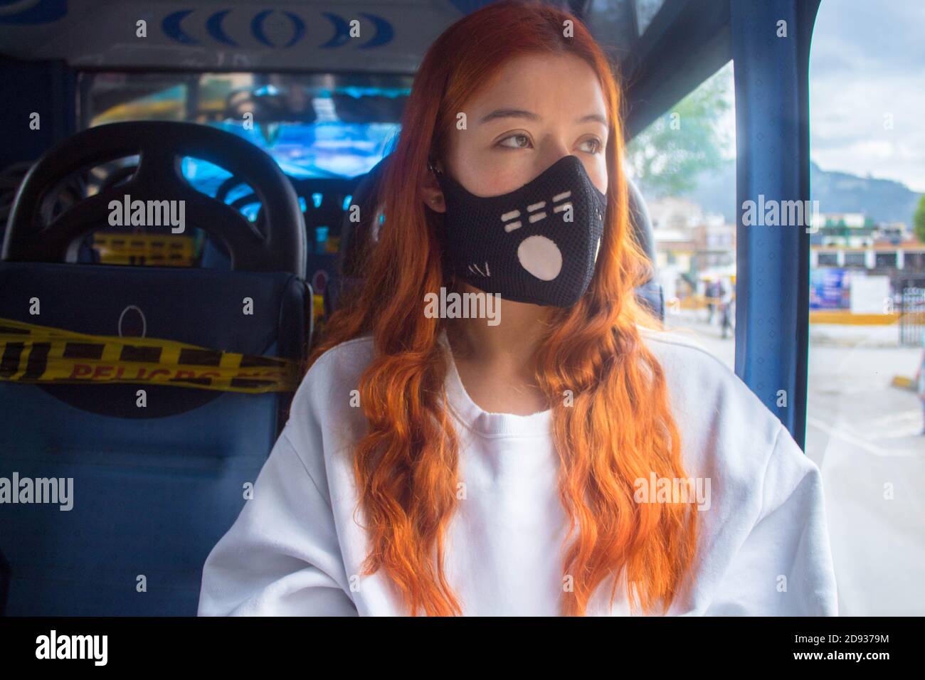 Female with a face mask and ginger hair sitting on the bus - concept of ...