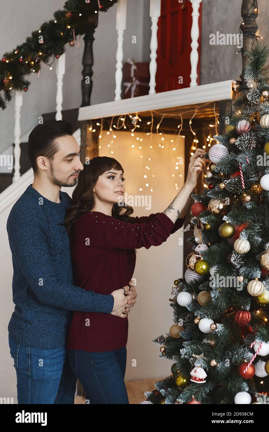 Beautiful romantic couple decorating Christmas tree in the living room ...