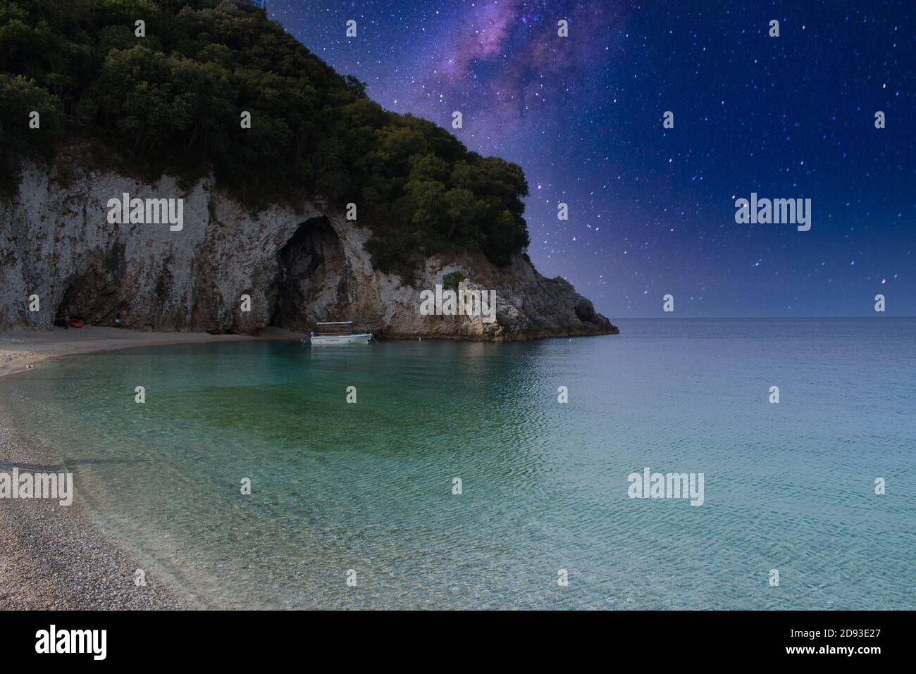 A beach with emerald sea water and a boat under a sky full of stars ...