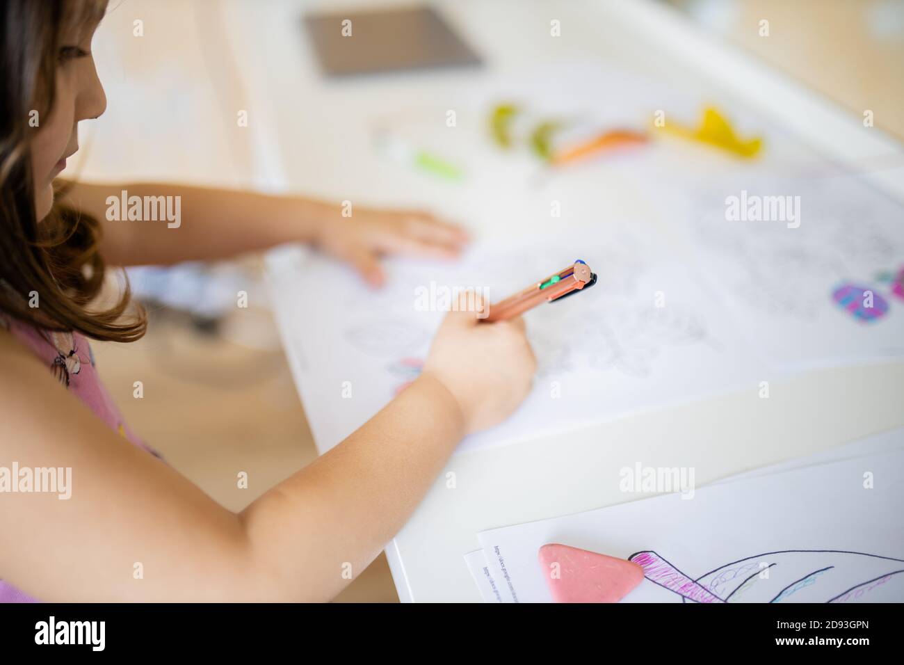 Little girl coloring different types of leaves on a paper sheet with a ...