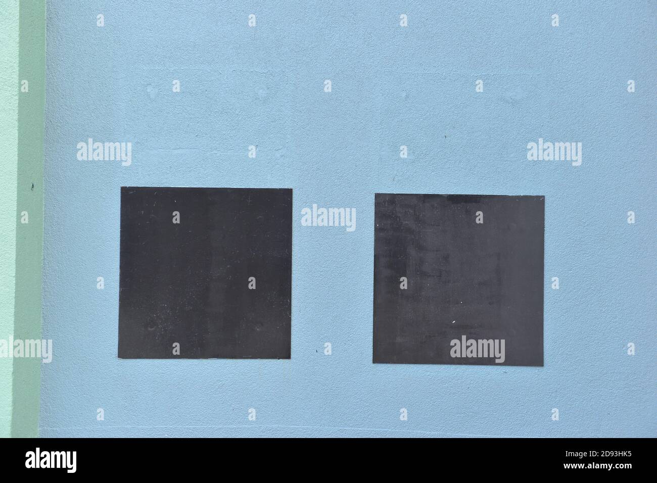 Two blank uneven square chalk boards used for advertising on a blue ...