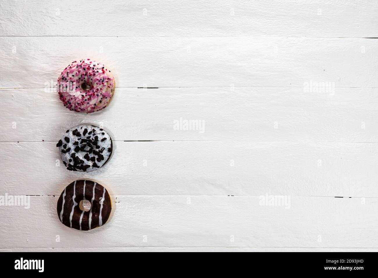 Colorful donuts on white wooden table. Sweet icing sugar food with ...