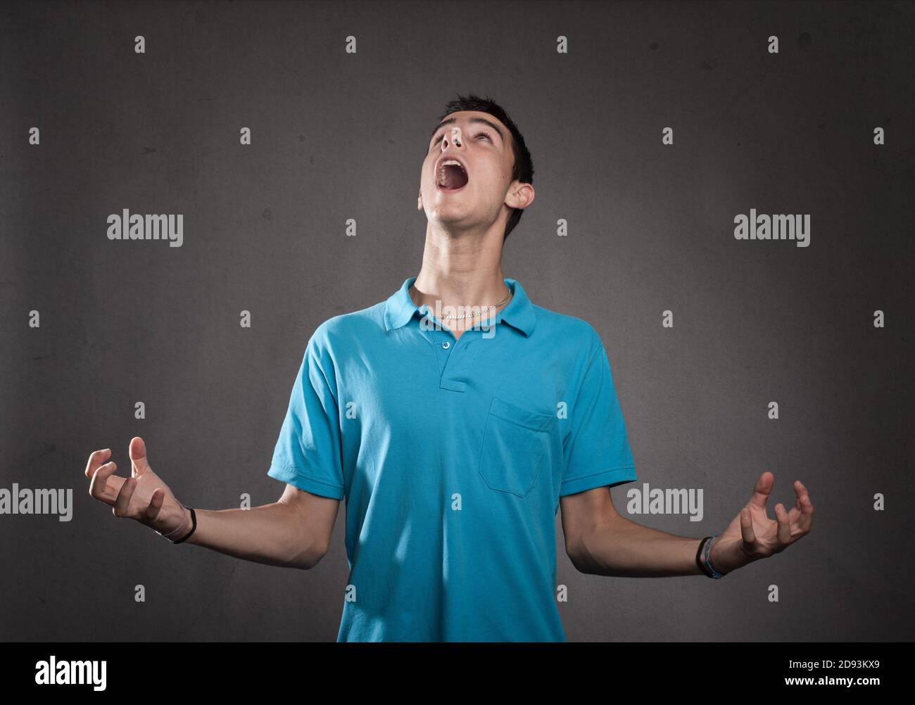 young man screaming on a grey background Stock Photo - Alamy