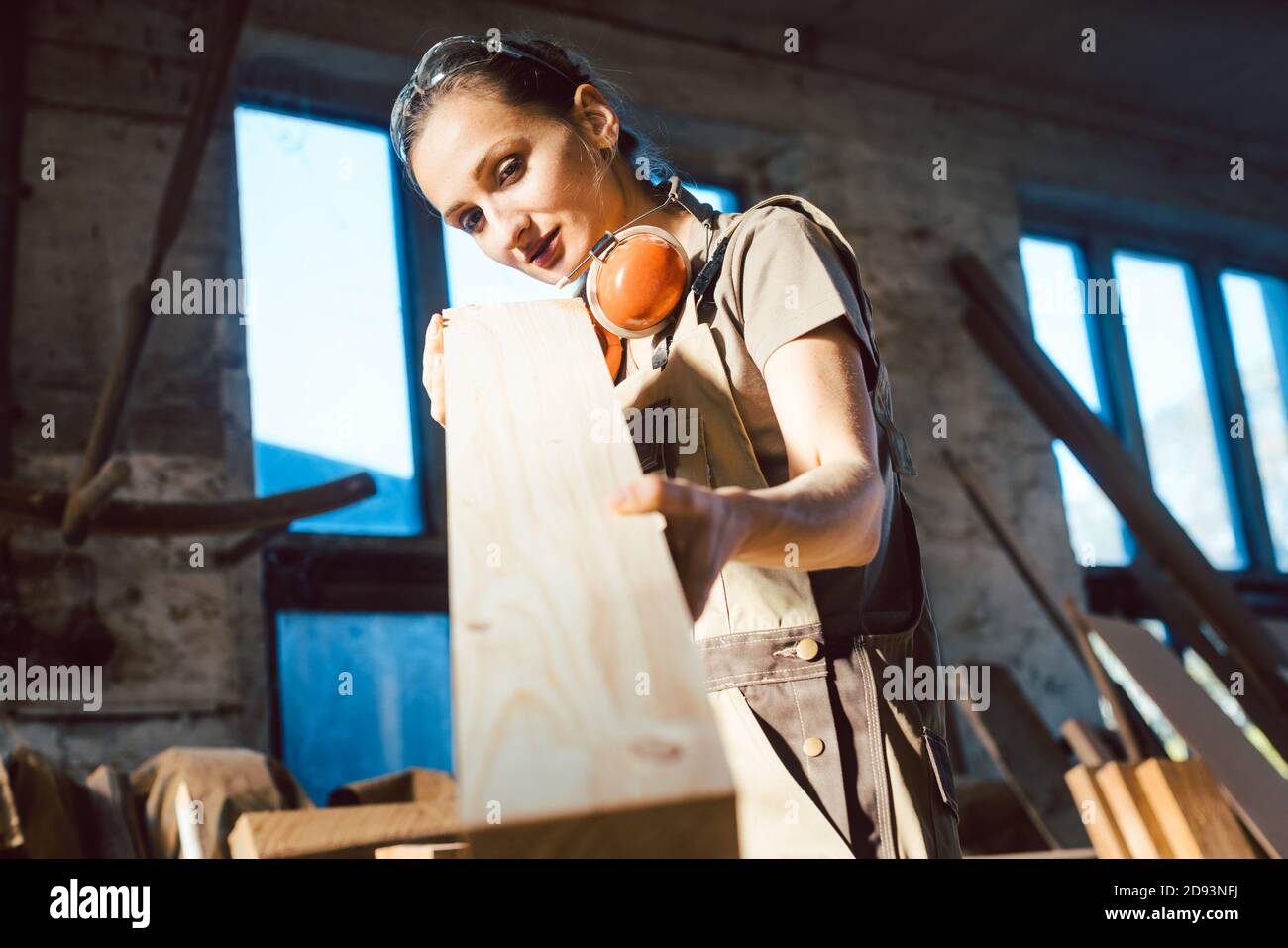 Beautiful woman carpenter checking quality of a plank Stock Photo - Alamy