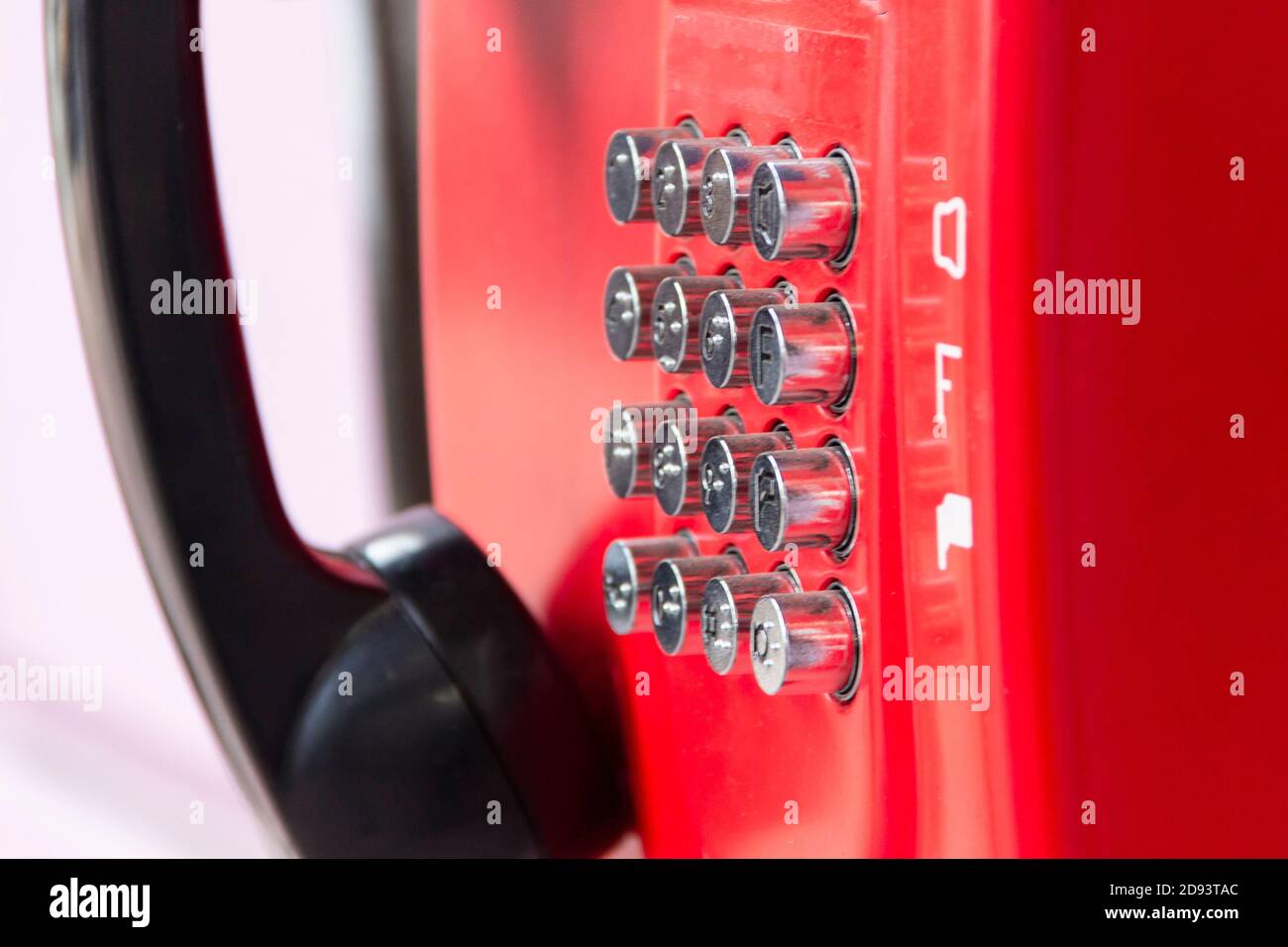 Red street payphone with round stainless steel buttons close-up. An ...