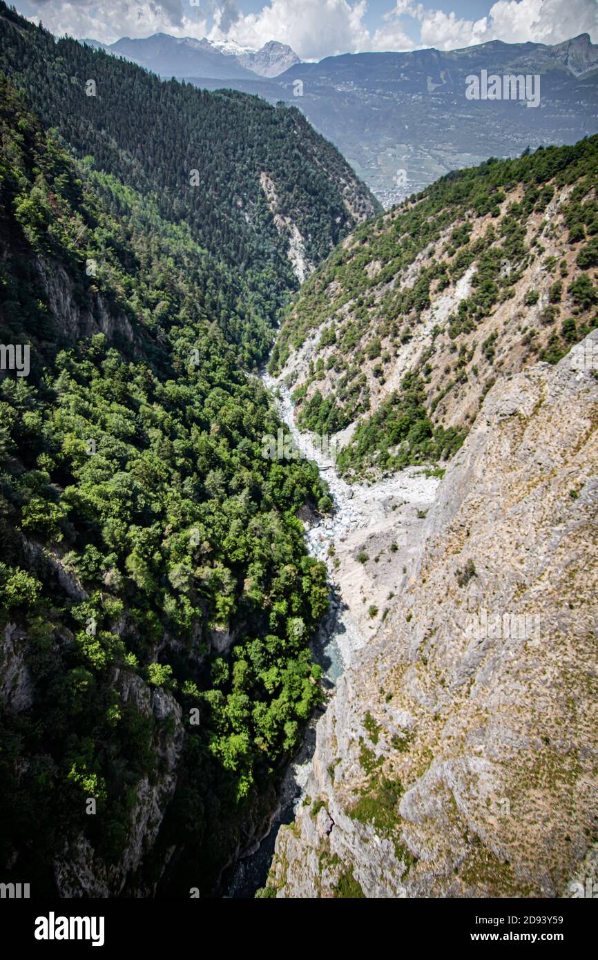 Aerial view of river flowing through forest in alpine valley in ...