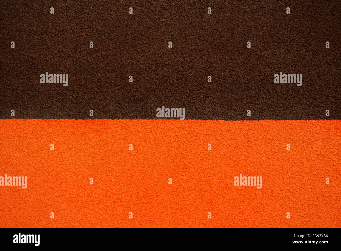 A horizontal stucco wall background divided in half with orange and ...